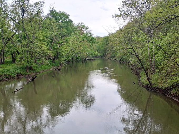 The Embarras River flows serenely beneath the bridge, its waters holding reflections of both sky and history.