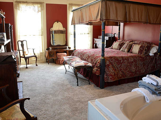 Rich red walls and period furnishings create a bedroom that transports you straight to the Victorian era.