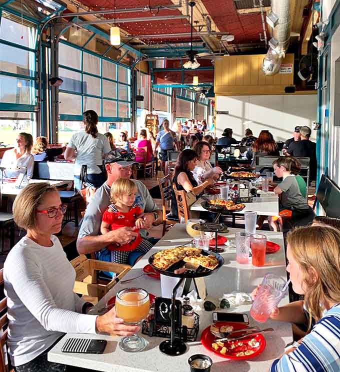 Garage doors open to create indoor-outdoor dining where families and friends gather to share pizzas, schooners, and lakeside memories.