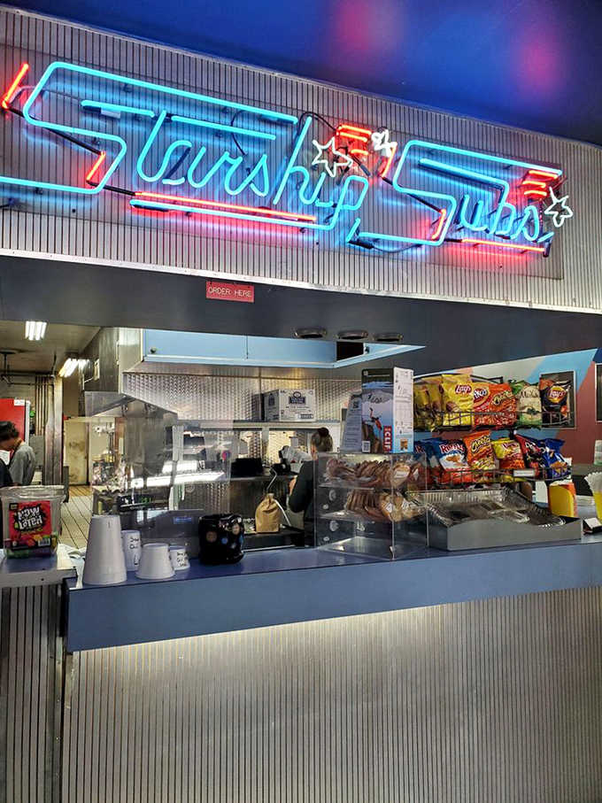 The counter glows with neon charm while staff members prepare sandwiches with the efficiency of a well-trained crew.