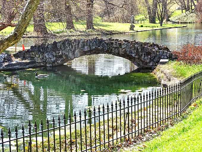 A rustic stone bridge arcs gracefully over reflective waters, creating a perfect circle when paired with its mirror image below.