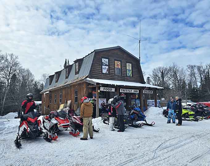 Winter transforms the Trestle Inn into a snowmobiler's haven, where cold adventurers gather to warm up and refuel before hitting the trails.