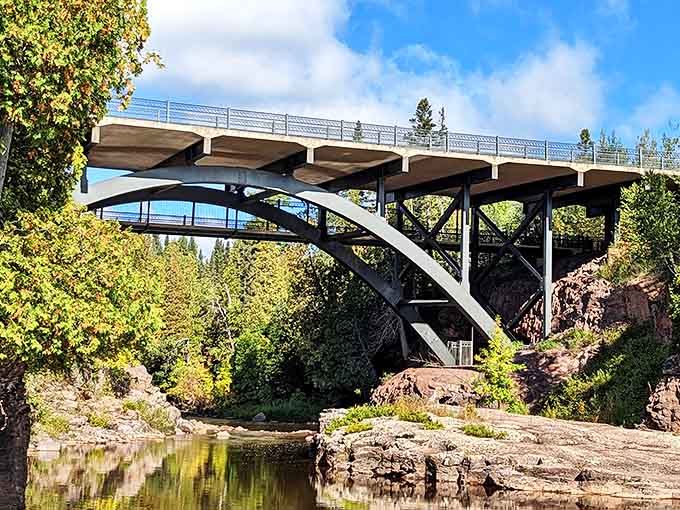 The graceful arch of the highway bridge frames the falls below, a perfect marriage of human engineering and natural splendor.