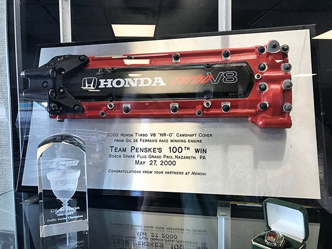 This Honda racing engine component celebrates Team Penske's 100th win, a milestone moment in motorsports history captured in mechanical memorabilia.