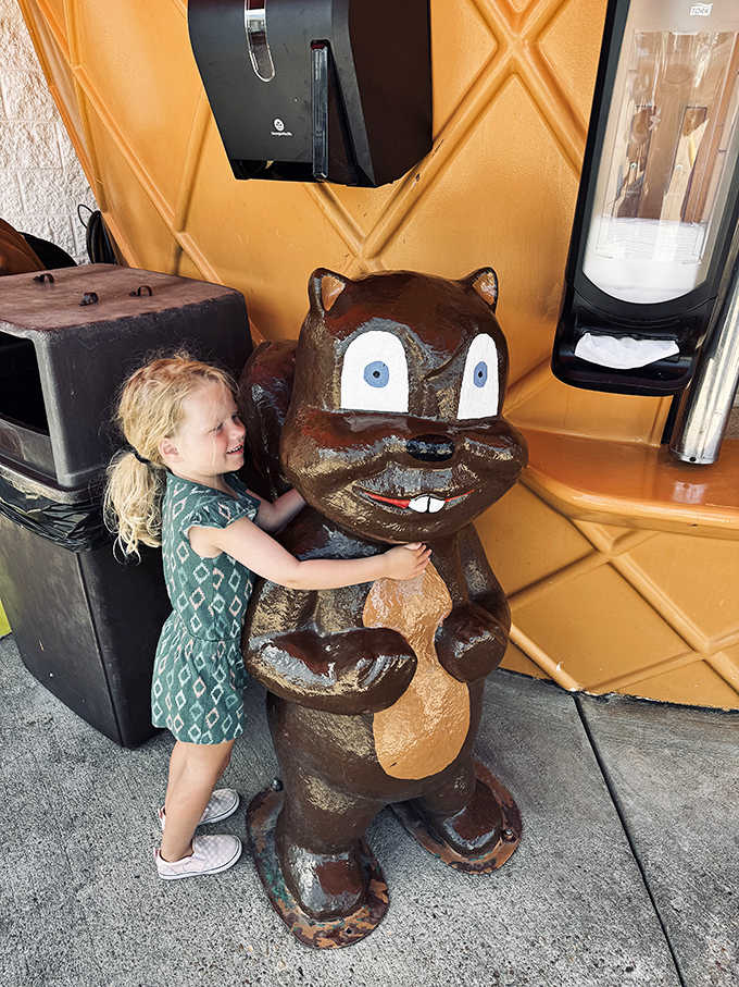 A young visitor embraces the friendly bear statue, creating the kind of childhood memory that will last far longer than the ice cream cone.