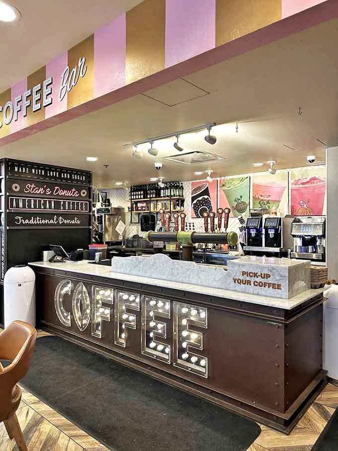 The coffee counter glows with promise, where baristas craft the perfect bitter companion to sweet donuts &ndash; a yin-yang relationship in breakfast form.