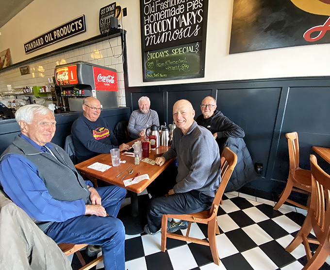 The morning regulars' table, where world problems are solved one coffee refill at a time and newcomers quickly become old friends.