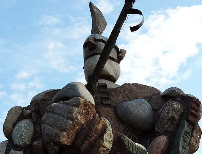 One guardian clutches a staff or spear, its stone muscles tensed as if ready to defend the river.