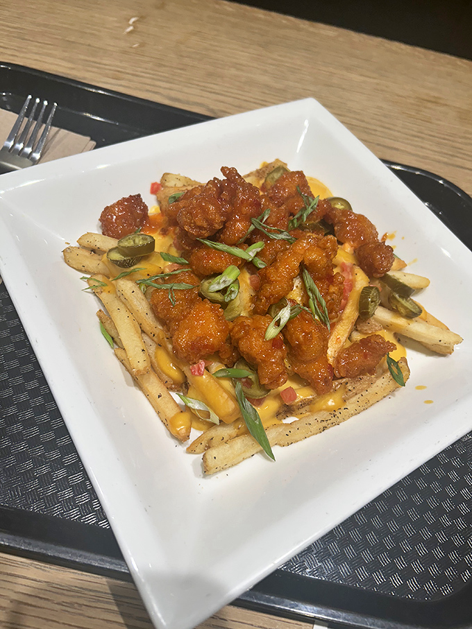 Crispy fries become a canvas for culinary creativity, topped with spicy sauce, melty cheese, and fresh garnishes for an indulgent shareable treat.