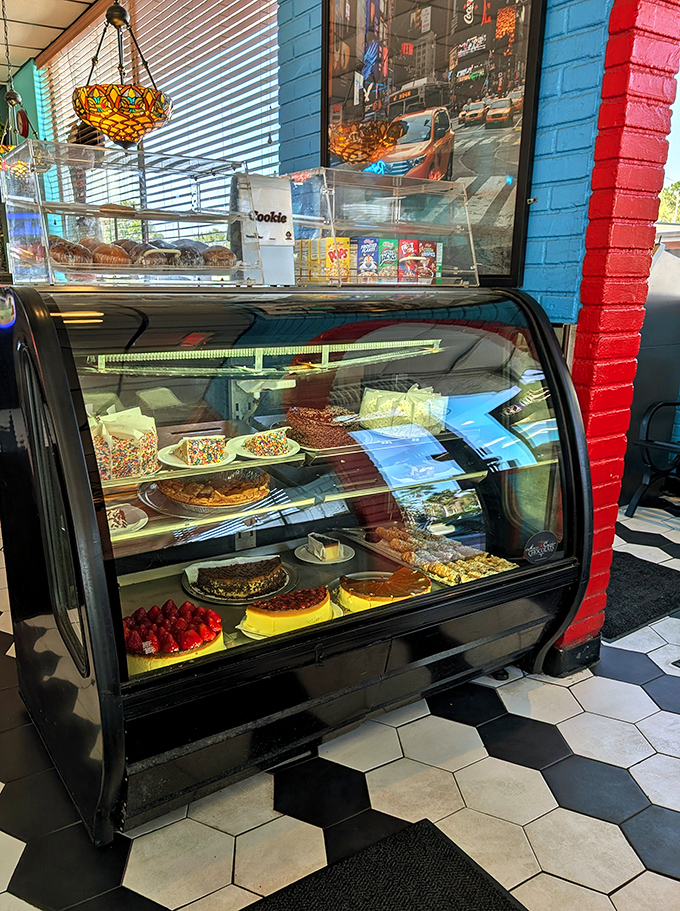 The dessert display case: adult version of pressing your nose against a toy store window. Each shelf offers a different path to sweet satisfaction.