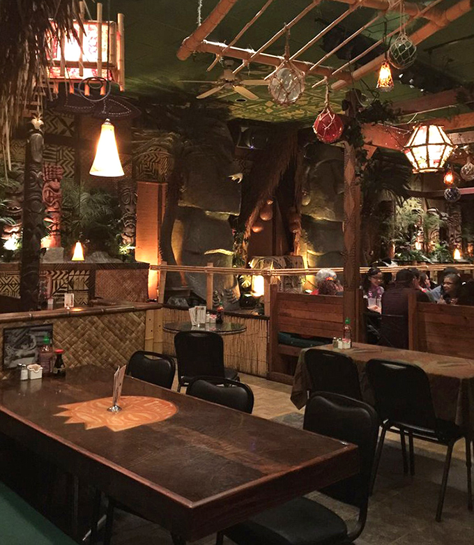 Intimate booth seating creates private tropical hideaways, where carved wooden elements and ambient lighting set the Polynesian mood.