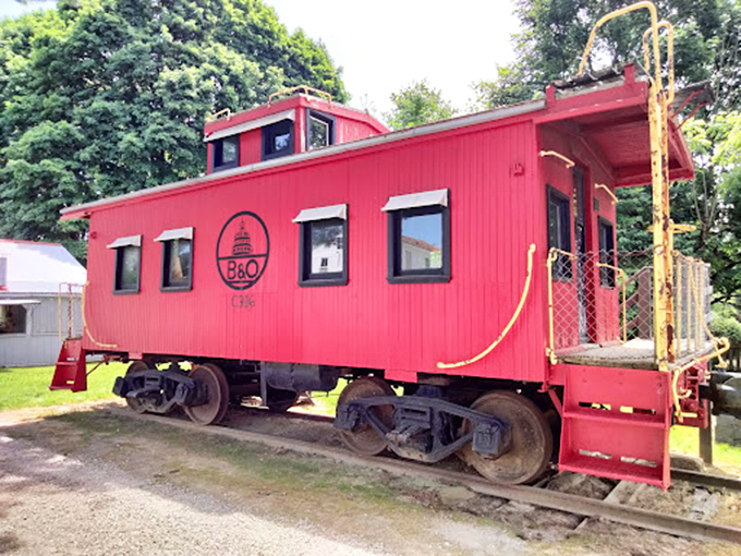 The bright red caboose stands as a monument to America's railroad era, its ladder and platform inviting imaginary journeys.