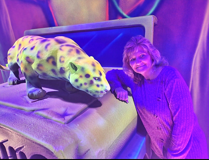 A visitor makes friends with a spotted jungle cat, both glowing under black lights &ndash; who says humans and fluorescent felines can't bond?