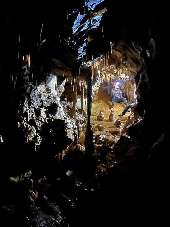 Dramatic lighting reveals the vast scale of this chamber, where humans become tiny figures in Earth's geological masterpiece.