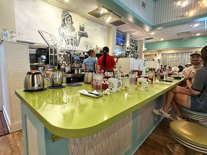 The counter buzzes with morning energy as staff craft coffee creations beneath vintage-inspired pendant lights and cheerful décor.