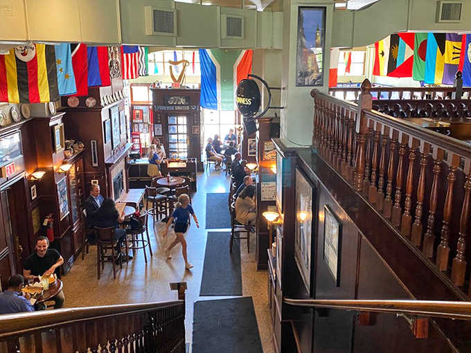 A bird's-eye view of the pub reveals multiple levels of British charm, with flags from Commonwealth nations adding splashes of color overhead.