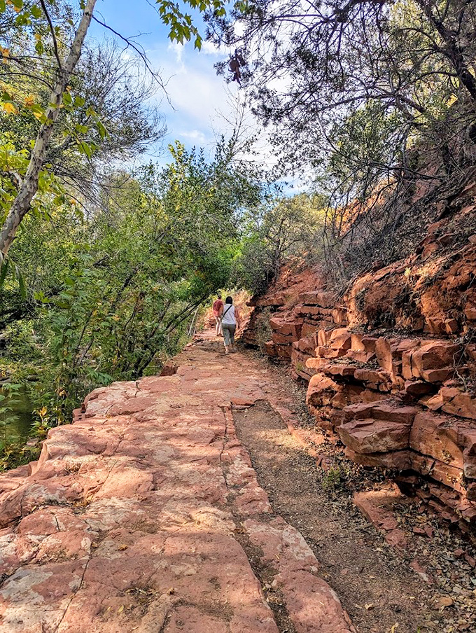 Hikers follow this ancient pathway, their footsteps joining thousands before them in a timeless journey through red rock country.