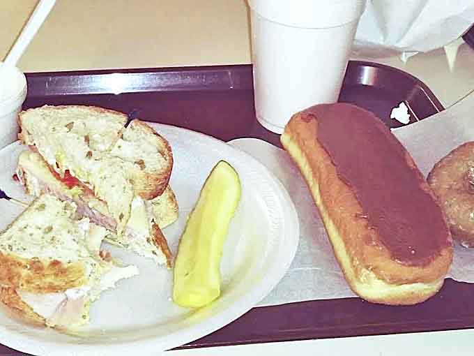 The perfect lunch trifecta: a hearty sandwich, a dill pickle for tang, and a chocolate-topped donut because you're an adult who makes good decisions.