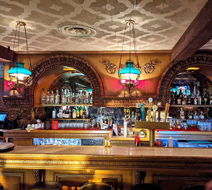 The ornate bar area, with its carved wooden arches and vintage lighting, invites patrons to settle in for a drink where generations have done the same.