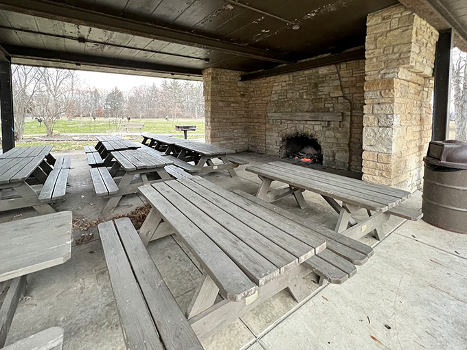 Weathered picnic tables await beneath the stone fireplace, inviting visitors to linger and enjoy meals with a view.