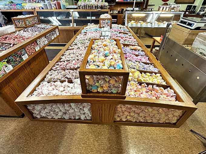 A wooden display case overflows with salt water taffy in every imaginable flavor, creating a colorful mosaic of chewy delights.