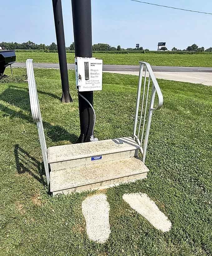 Two concrete footprints mark the spot where visitors should stand, with steps leading to the token slot that awakens the dragon's fiery breath.
