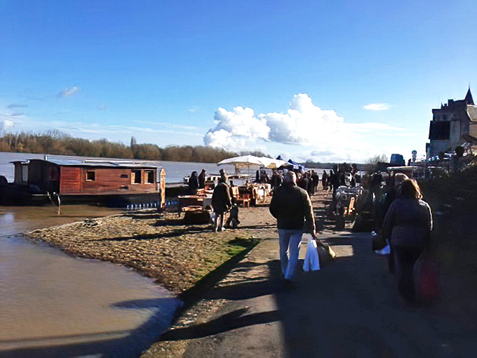 Riverside market browsers discover treasures along the water's edge—proving that sometimes the best shopping experiences happen outside traditional walls.