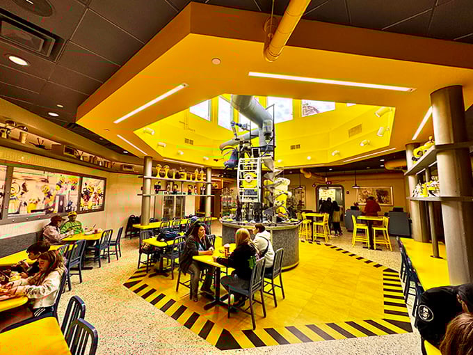 The central dining area buzzes with energy beneath a soaring yellow ceiling, where industrial-chic meets cartoon laboratory in perfect harmony.