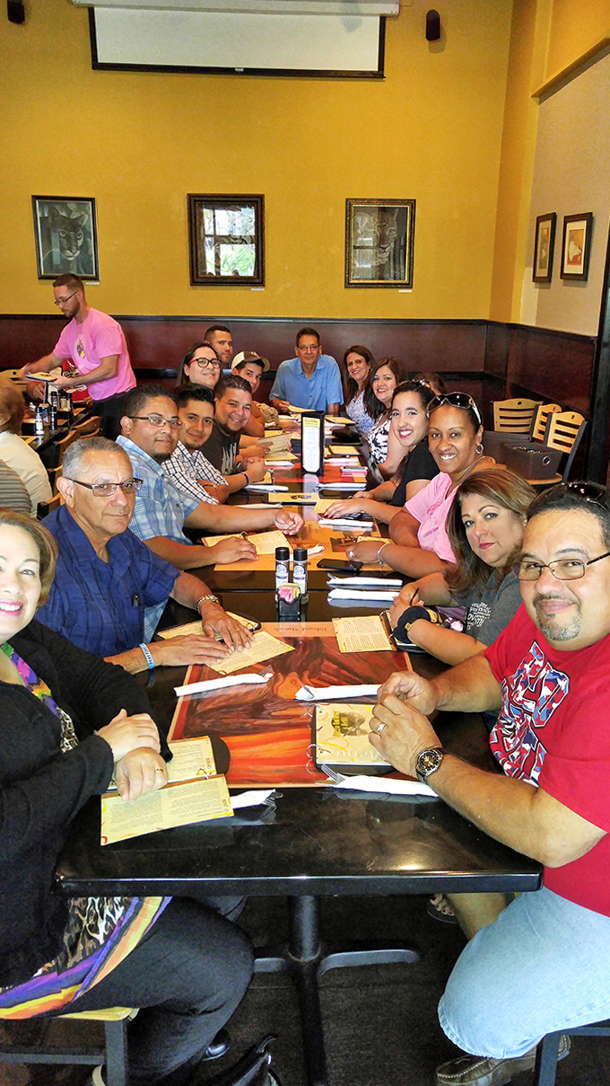 Happy diners gather around a long table, proving that good food and art create the perfect backdrop for human connection.