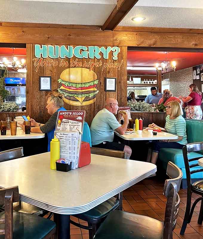 Diners of all ages gather under the watchful eye of a giant burger mural, proving that Andy's bridges generations with its timeless appeal.