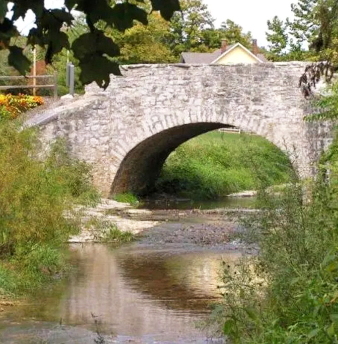 The historic one-lane stone arch bridge has connected the village for generations &ndash; its graceful curve reflected in waters that have flowed since before America existed.