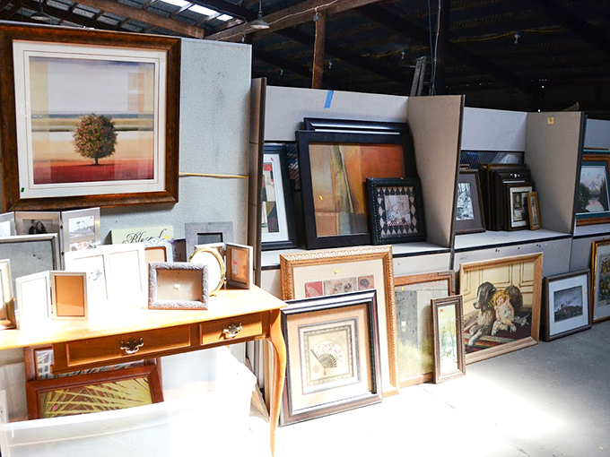 Framed artwork leans in patient rows &ndash; where someone's discarded decor becomes another's perfect wall statement.