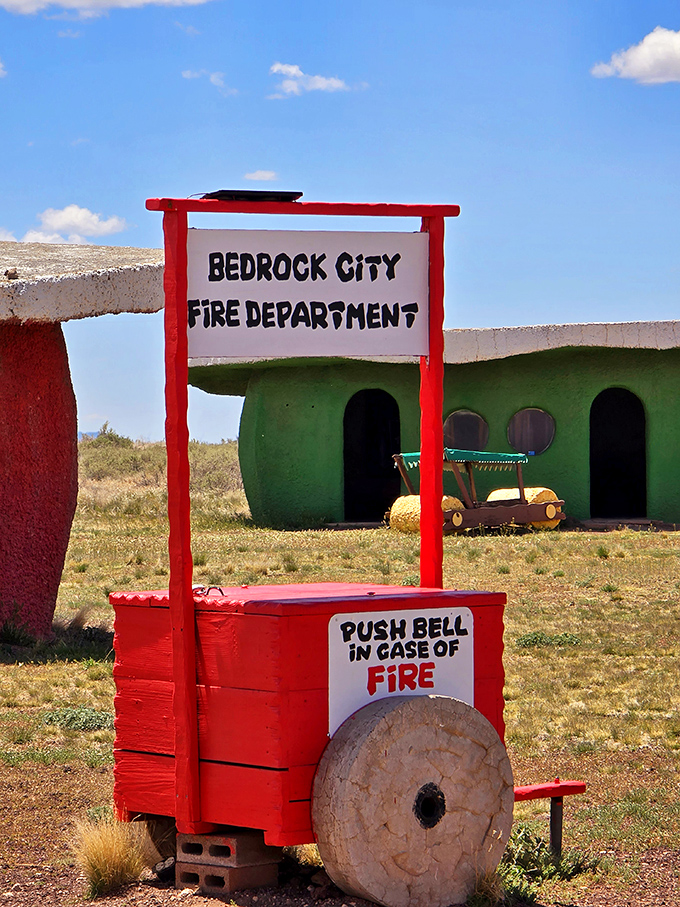 Bedrock's fire cart stands ready for Stone Age emergencies, its "Push Bell in Case of Fire" sign both charming and hilariously impractical.