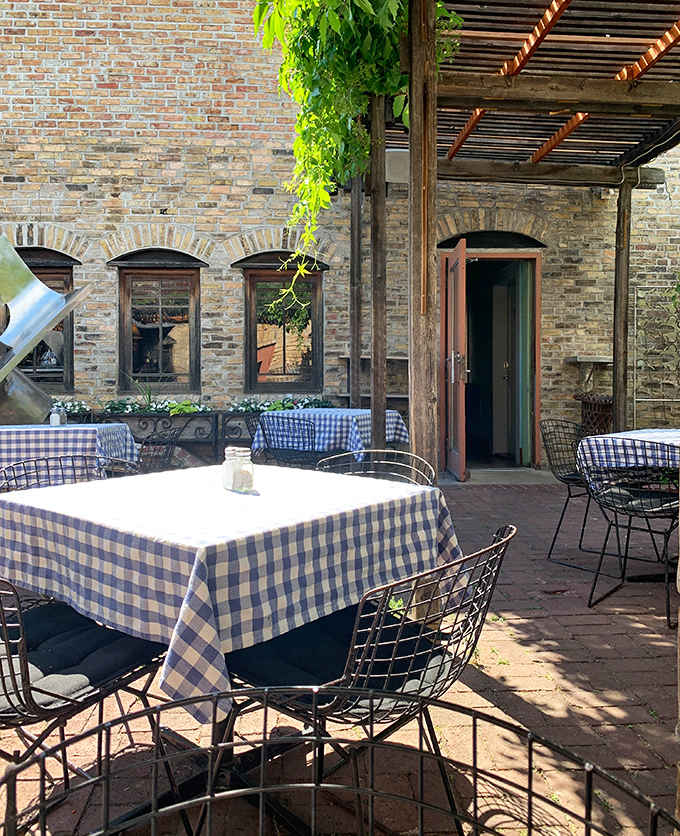 Al fresco dining takes on European charm with the restaurant's signature blue-checkered tablecloths against rustic brick surroundings.
