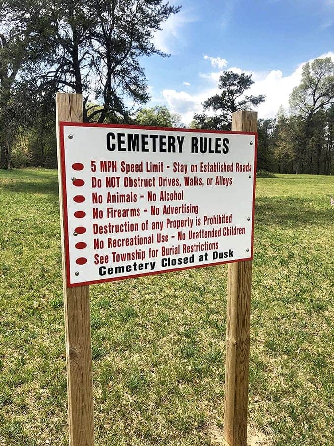 The cemetery rules sign stands as a necessary guardian against the unfortunate vandalism that has plagued this historic site.