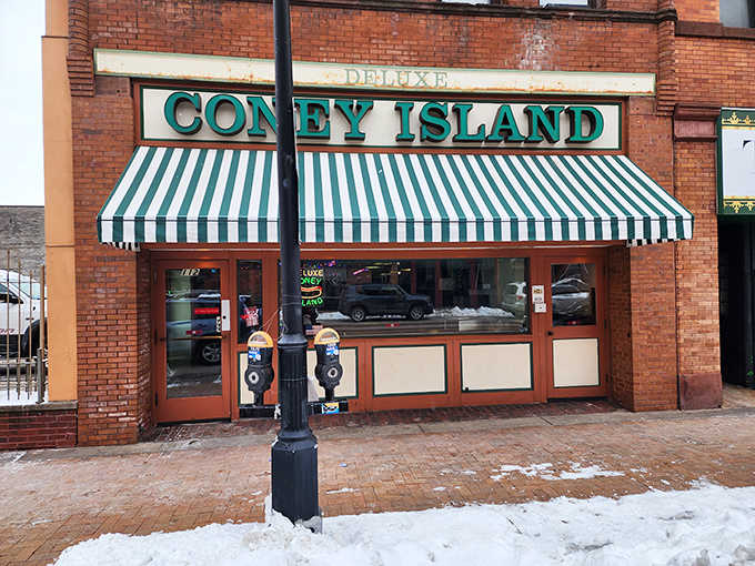 Winter transforms the storefront into a snow-framed haven of warmth, the green-striped awning standing out against Duluth's brick and white landscape.