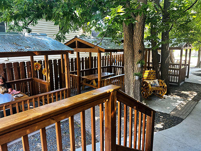 Wooden booths nestled under shade trees offer a secluded spot to savor every bite of your Caribbean feast.