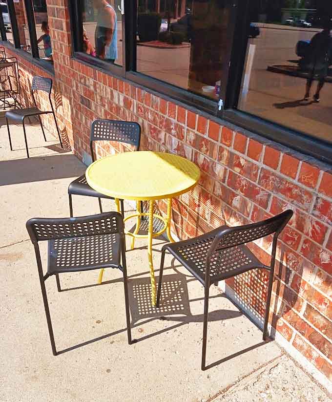 The sunny sidewalk seating where summer mornings taste even sweeter &ndash; a front-row seat to Gurnee's morning parade with donut in hand.
