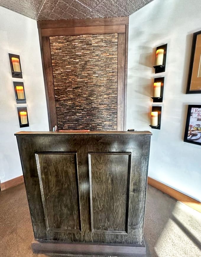 The hostess stand sets the tone with its blend of rustic wood, stone accents, and warm lighting from decorative wall sconces.