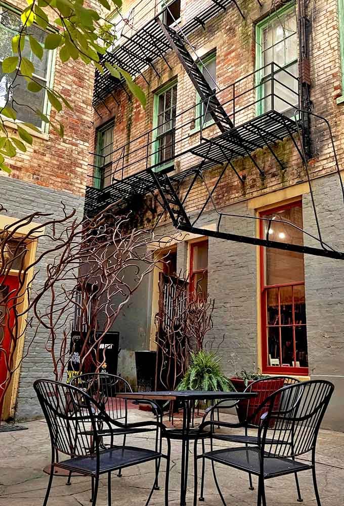 The hidden courtyard feels like stumbling into a secret garden where brick walls tell stories and wrought-iron chairs invite lingering conversations.