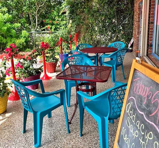The charming outdoor seating area offers a pleasant spot to enjoy your sandwich amid colorful chairs and potted flowers.