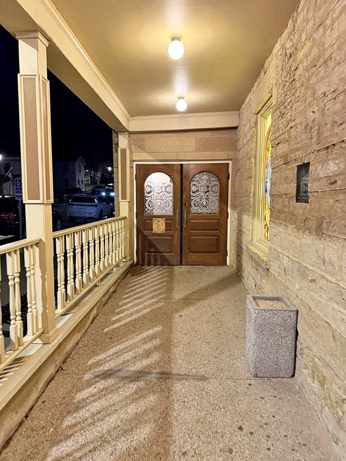Evening shadows play across the welcoming entrance porch, where wooden railings and stone foundations speak to craftsmanship from another century.
