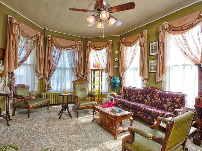 The parlor's olive walls, ornate draperies, and period furniture create the perfect setting for conversation or quiet contemplation.