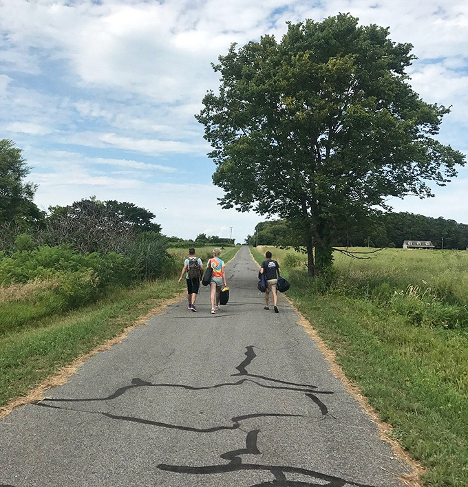 Quiet rural road with hikers, where open fields and an easy walking pace shape the journey.