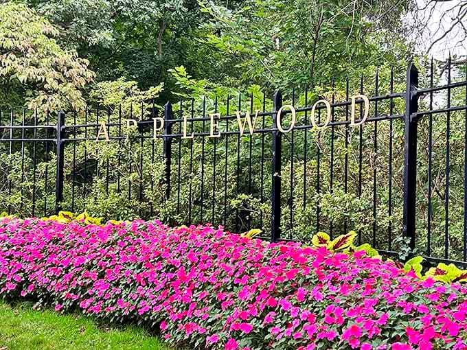 The estate's elegant iron fence announces "Applewood" amid vibrant flowers &ndash; a grand entrance that promises the magic waiting just beyond.