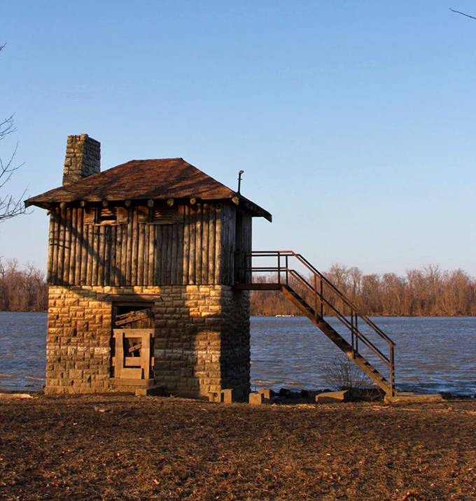 This charming stone cabin stands sentinel by the water, a testament to craftsmanship that has weathered decades of river seasons.