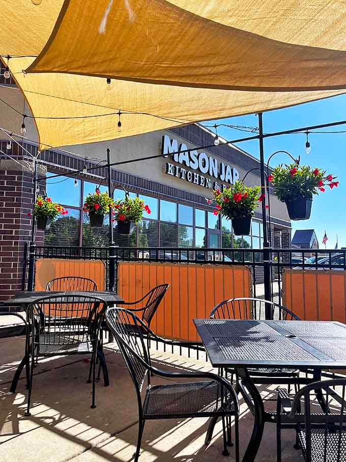 The outdoor patio invites lingering under canvas sails, where summer evenings stretch deliciously into twilight.