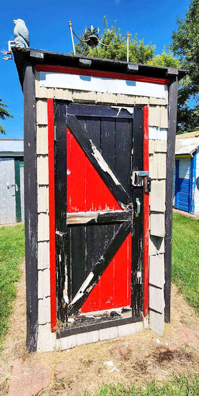 This striking red and black door design proves that even outhouses can have architectural flair and dramatic color schemes.