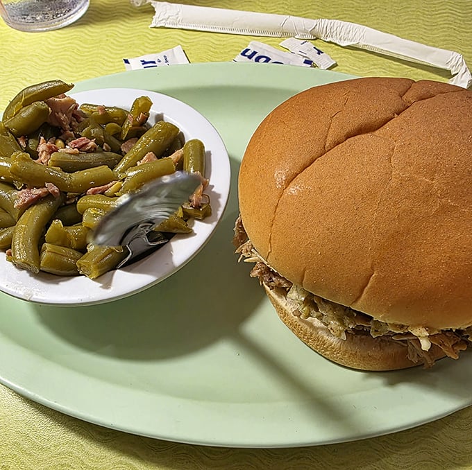 Green beans with ham hock alongside a pulled pork sandwich &ndash; simple side dishes elevated to star status through traditional cooking methods and quality ingredients.