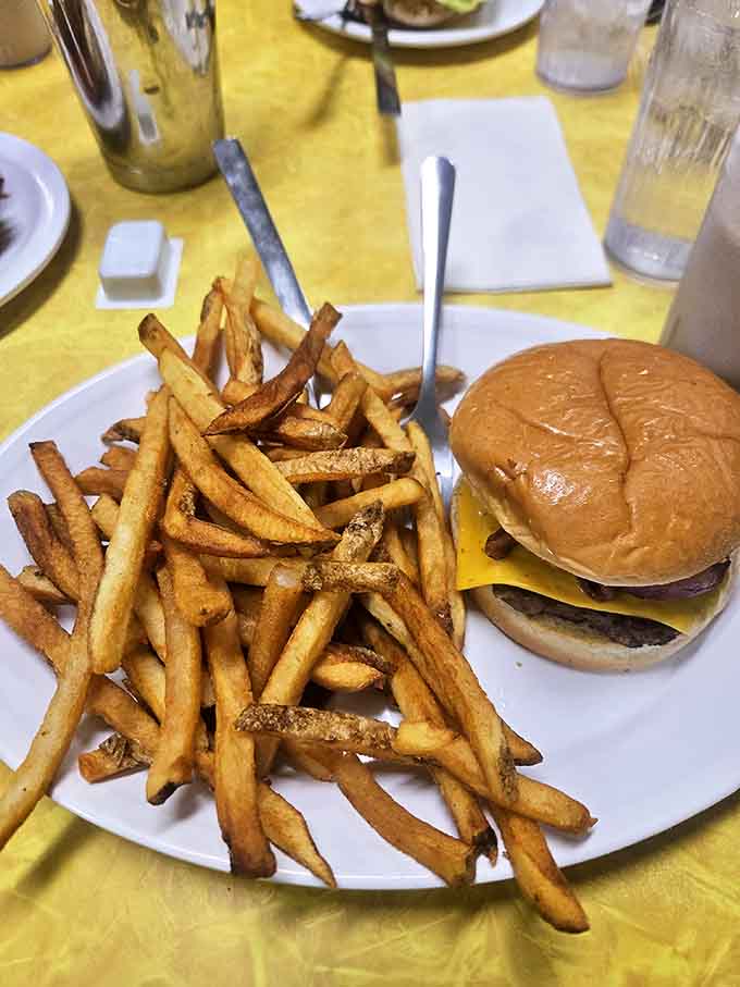 The burger and fries – hand-formed patty on a pillowy bun with fries so perfectly golden they deserve their own trophy.